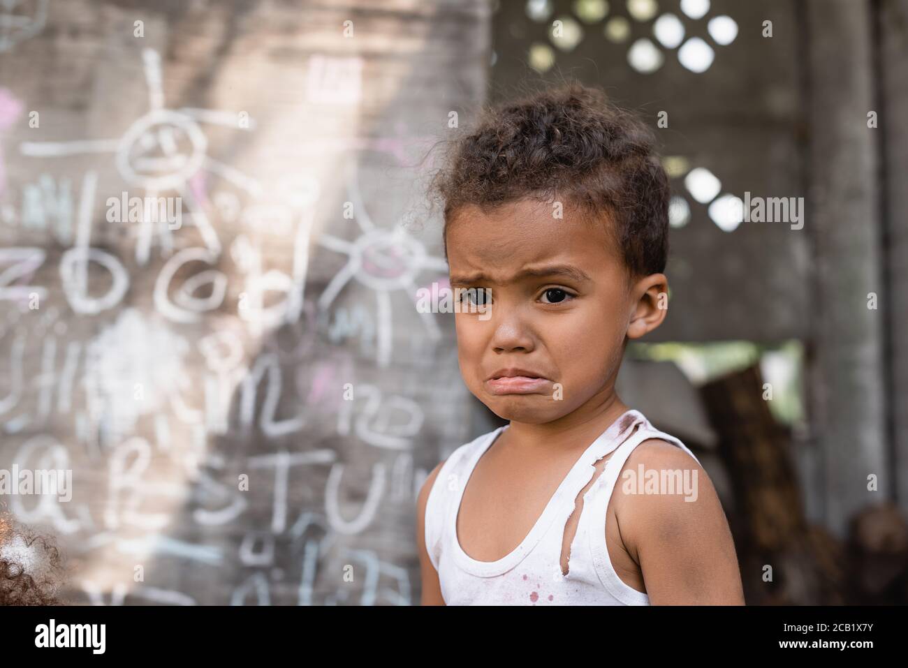 selective focus of poor african american boy crying near chalkboard ...