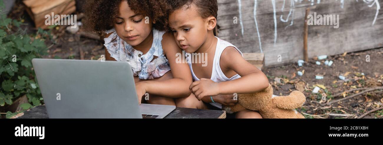 panoramic orientation of poor african american kids using laptop ...