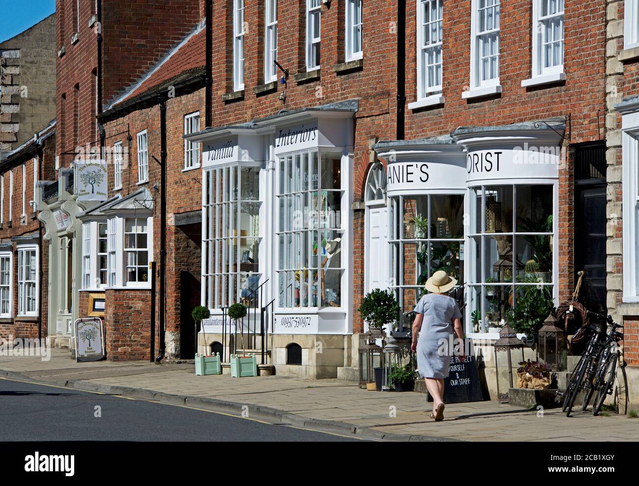 Woman walking past shops on Bridge Street in Tadcaster, North Yorkshire ...