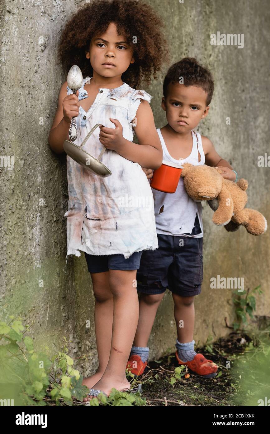 Selective focus of homeless african american kids holding plate and cup ...