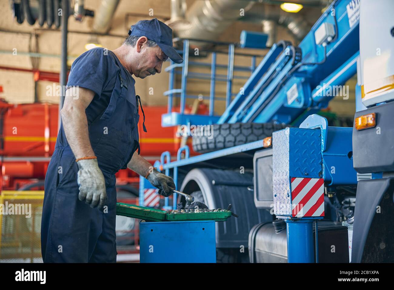 Attentive mechanic taking necessary instrument during work Stock Photo ...
