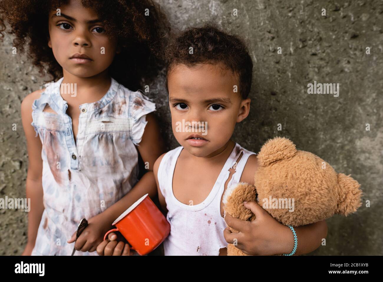 Poor african american children in dirty clothes with metal cup and ...