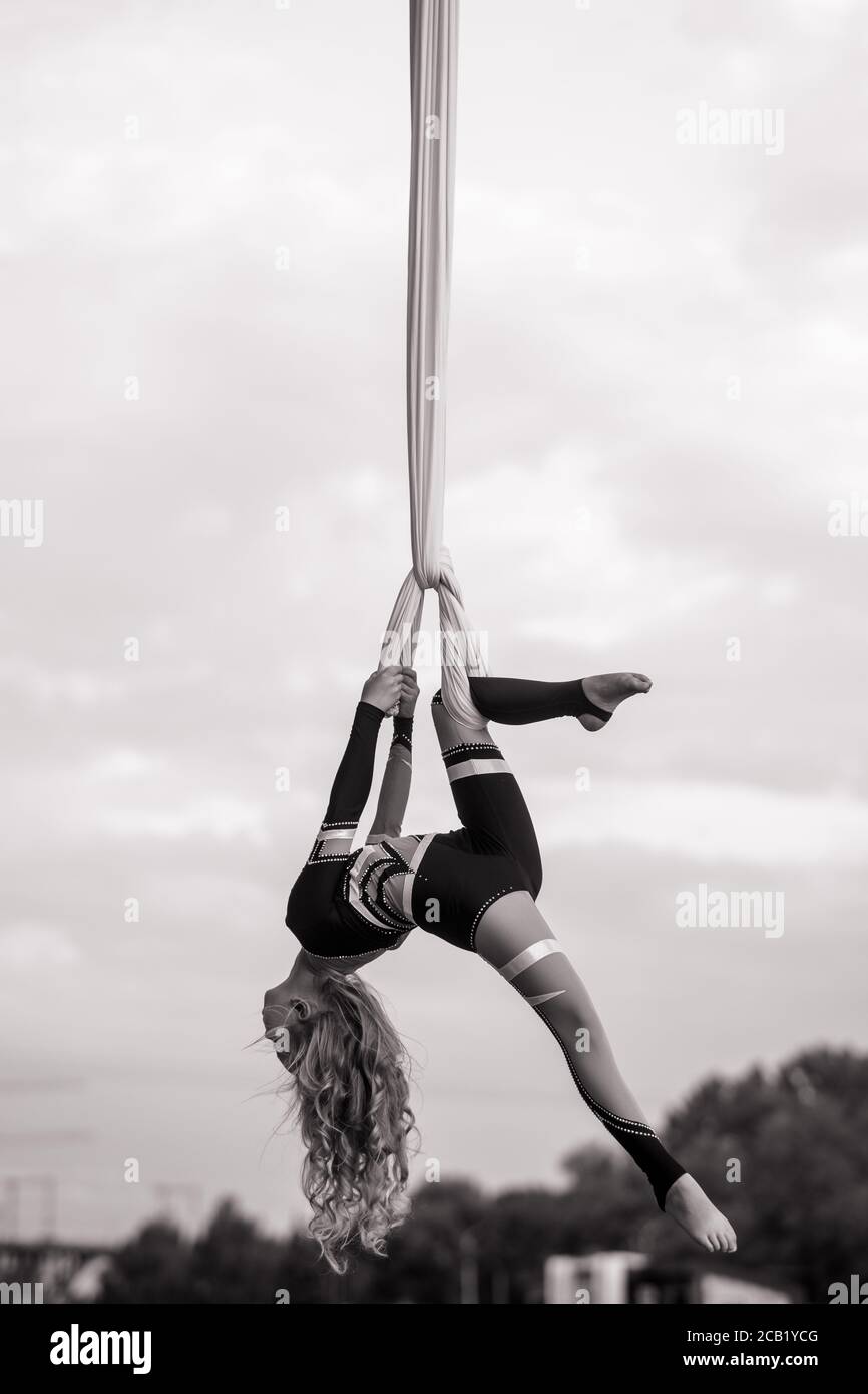 Child girl aerialist performs acrobatic tricks on hanging aerial silk ...