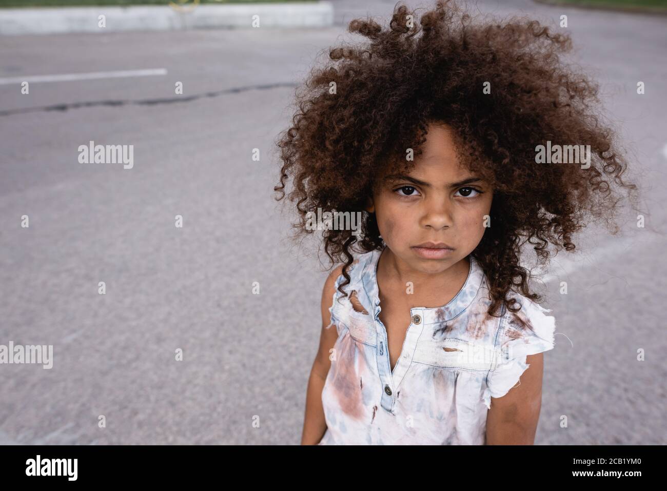 Poor african american child with messy face looking at camera on urban ...