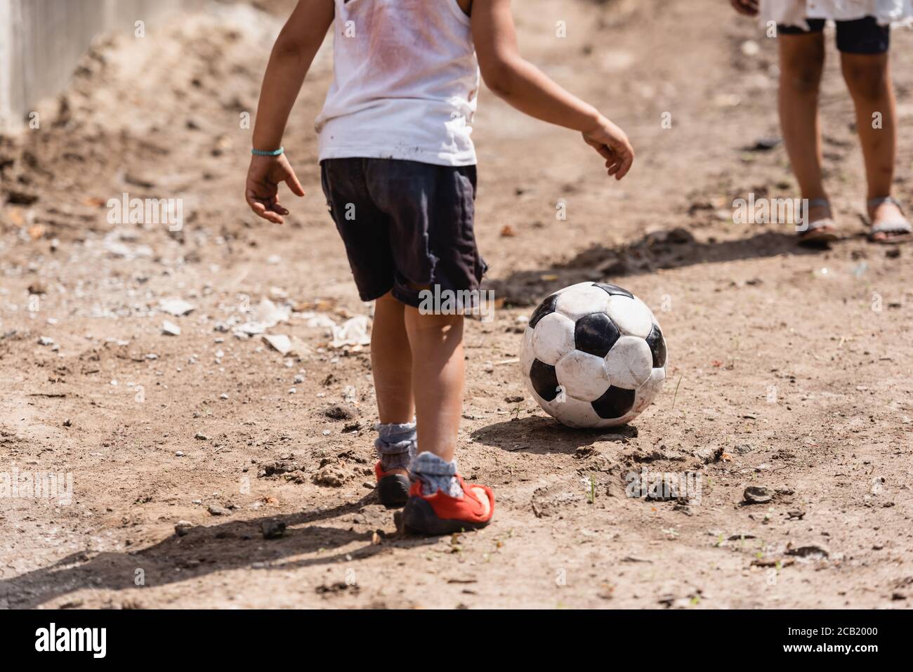 Cropped view of poor african american boy playing football near sister ...