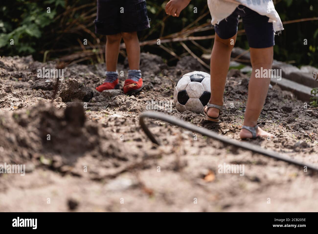 Cropped view of poor african american children playing football on ...
