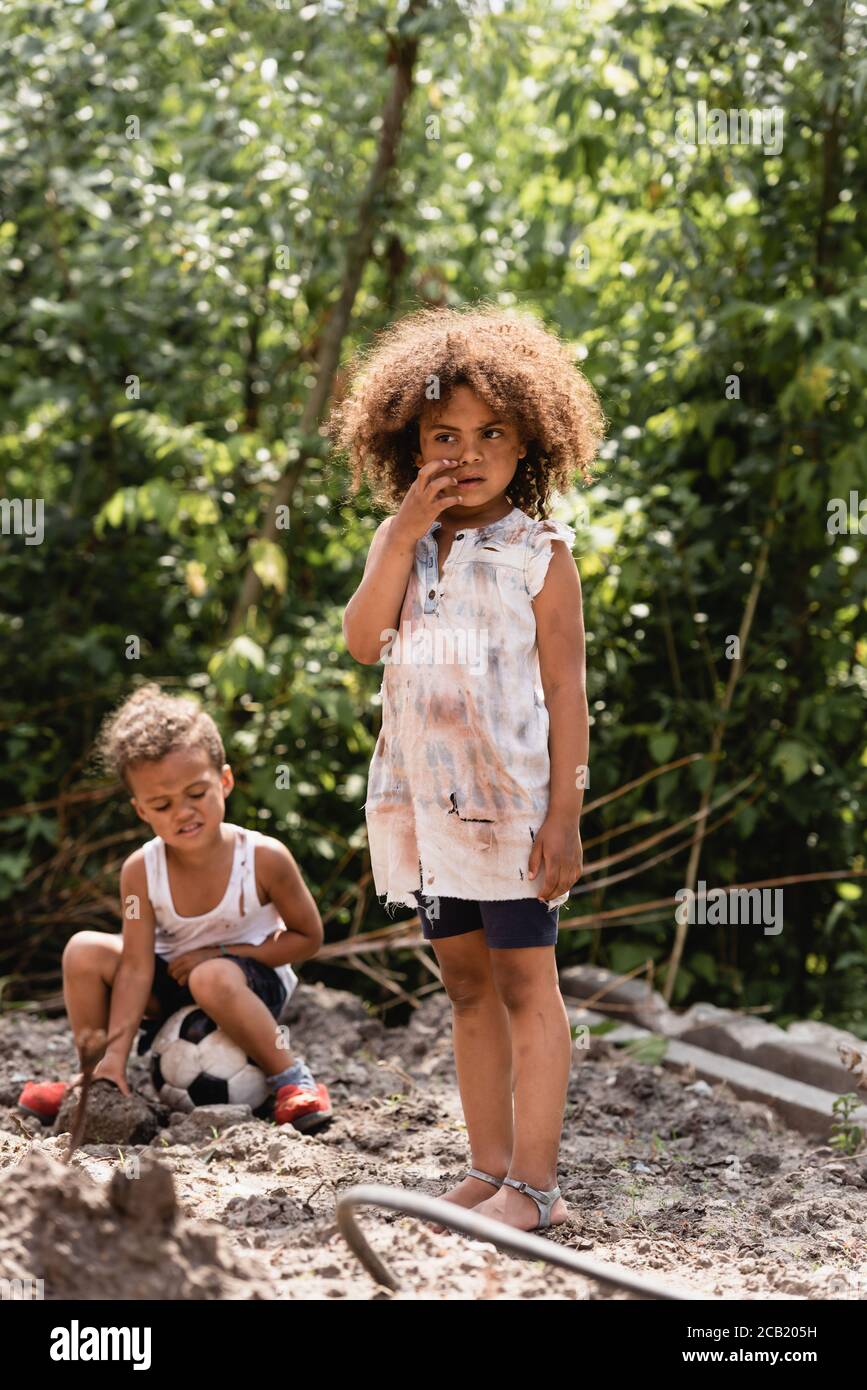 Selective focus of poor african american kid in messy clothes standing ...
