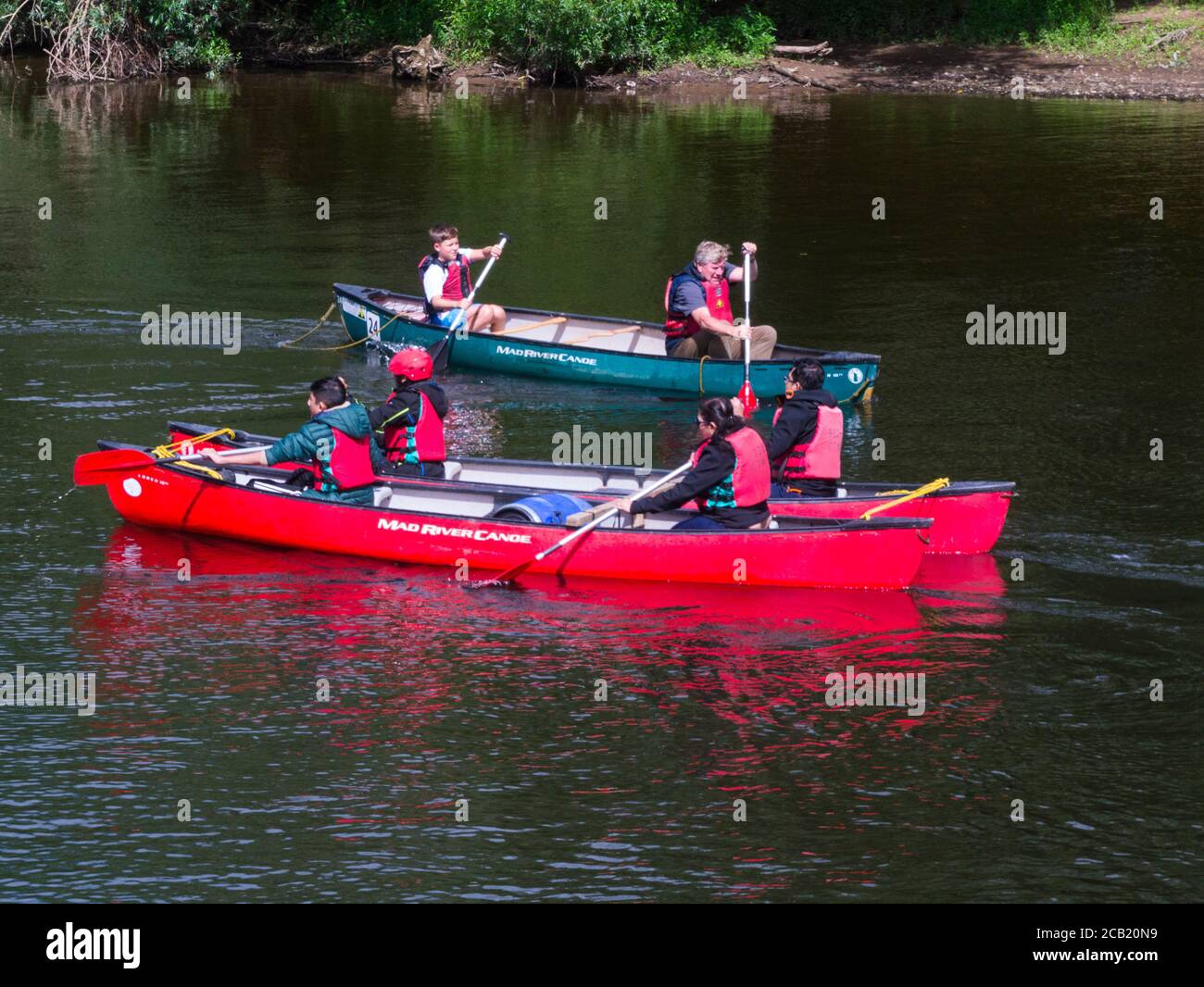 A family group and a father and son paddling Mad River Canoes passing ...