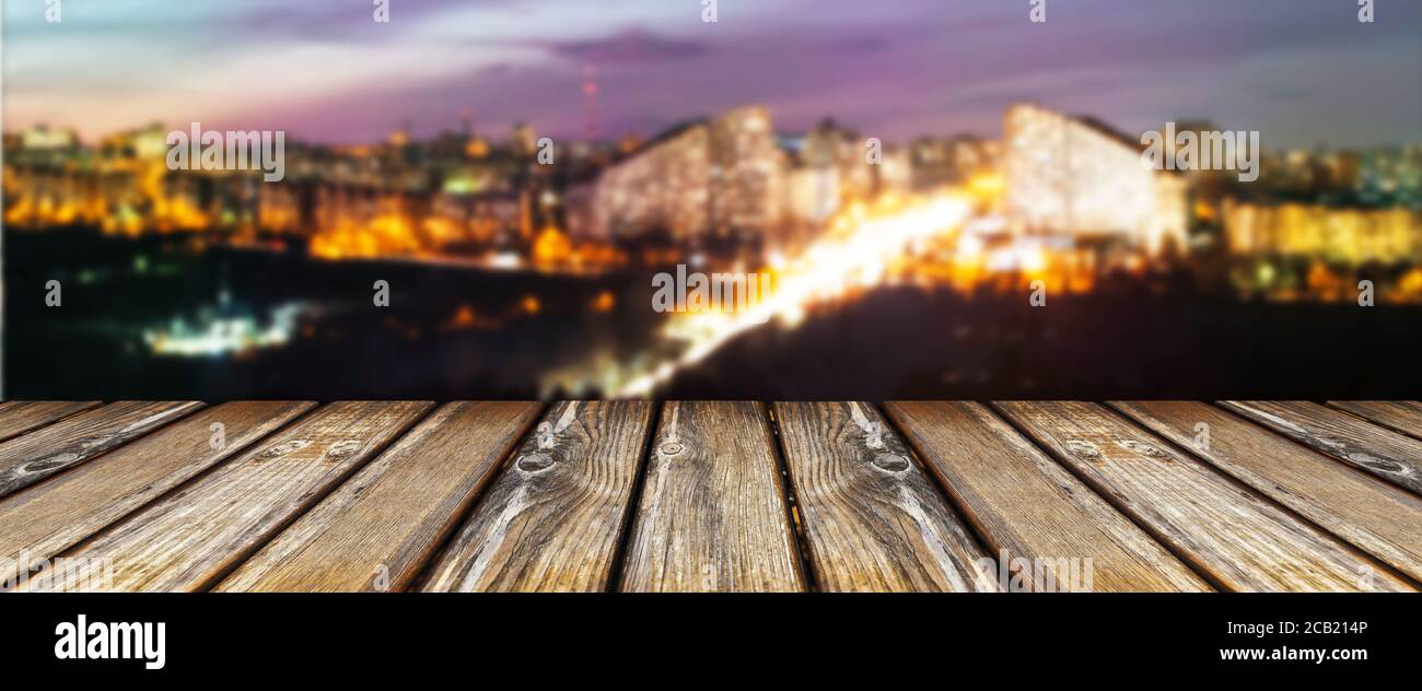empty wooden table on the background of the night city, panoramic image ...