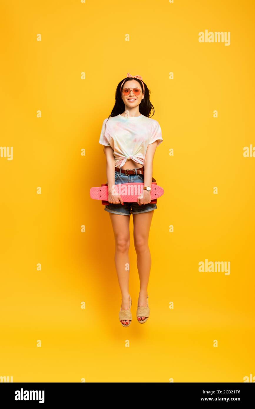 happy stylish summer brunette girl jumping with pink penny board on ...