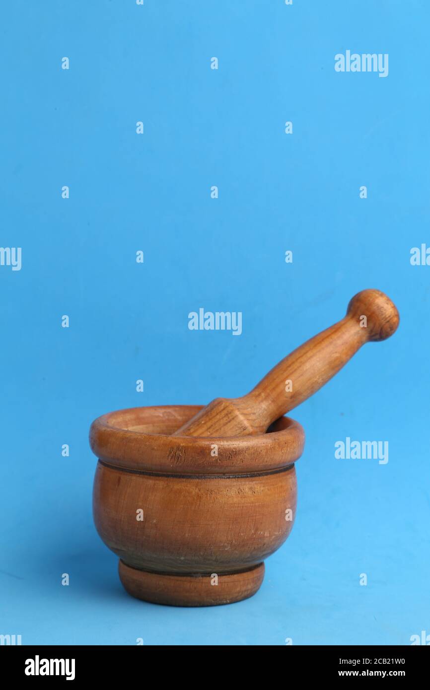Vertical shot of a wooden mortar and pestle isolated on a blue ...