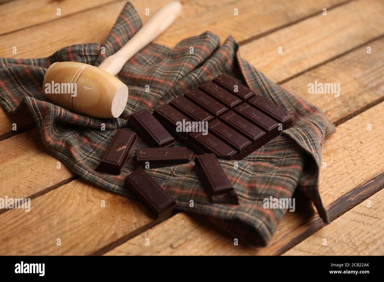 Closeup of a broken chocolate block beside a wooden mallet on top of a ...