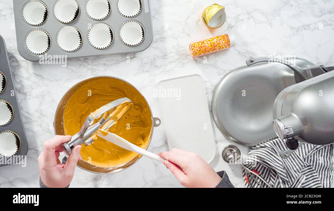 Flat lay. Scooping pumpkin spice cupcake batter with batter scoop into ...