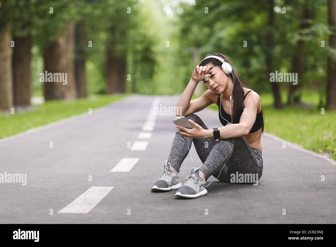 Tired Asian Runner Girl Resting On Path In Park After Jogging Stock ...