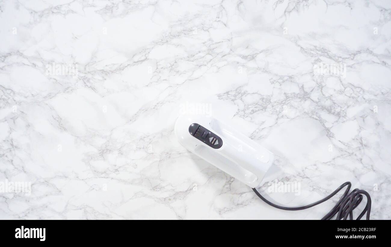 Flat lay. Step by step. White hand mixer on a marble kitchen surface ...