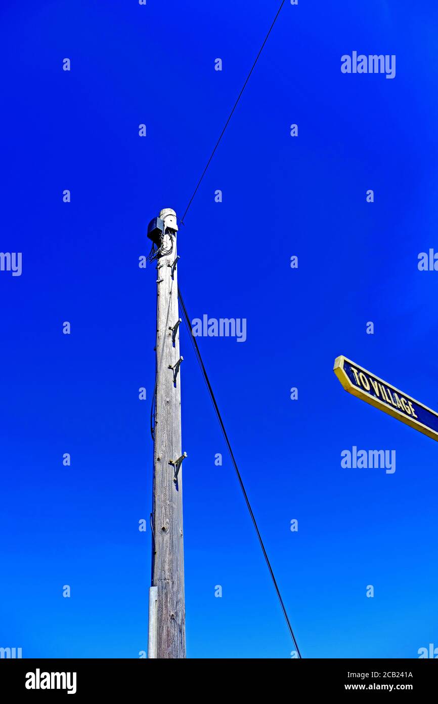 Single wooden pole simple comms power line and cables with village sign ...
