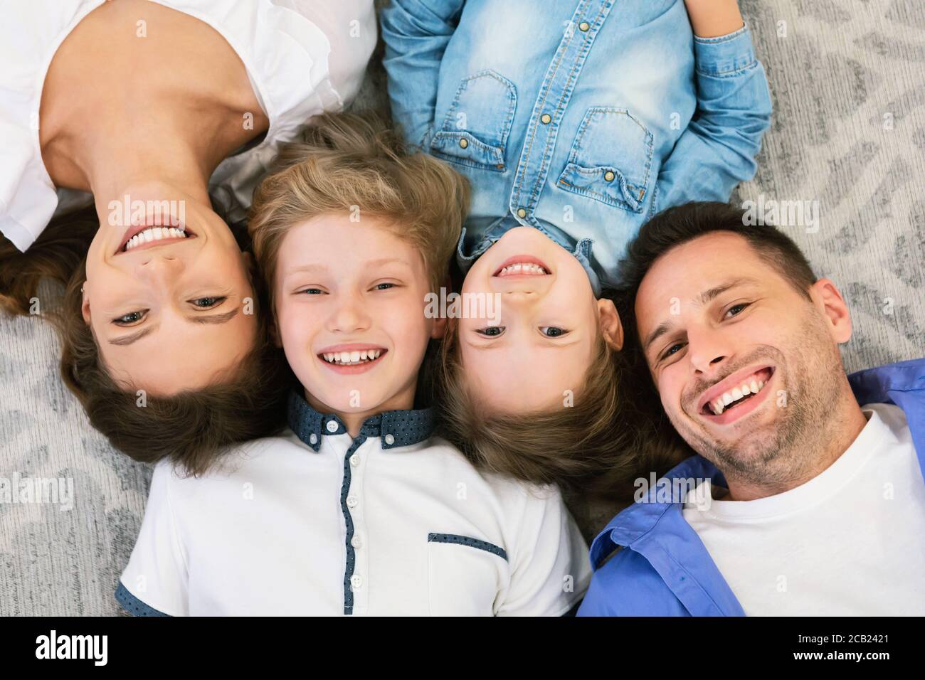 Smiling Parents And Children Lying On Floor Posing Indoors, Above-View ...