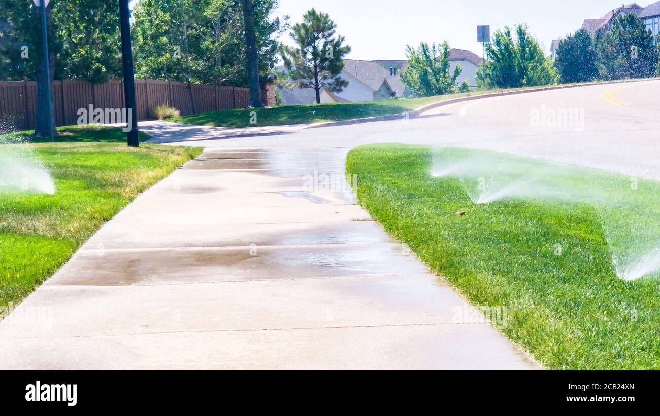Irrigation of the green lawn with sprinkle system Stock Photo - Alamy