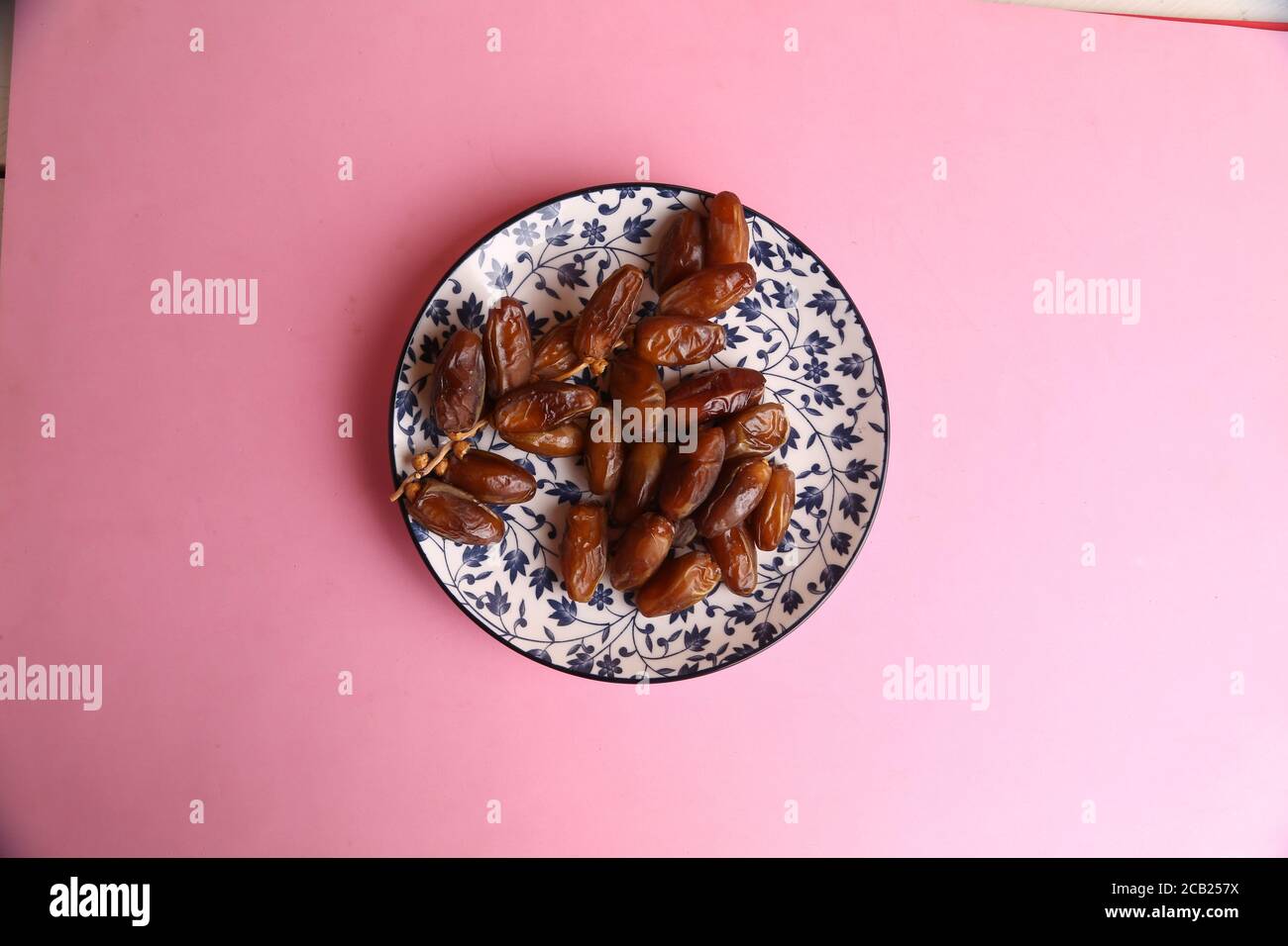 Top view of a plate of dry fruits dates isolated on a pink background ...