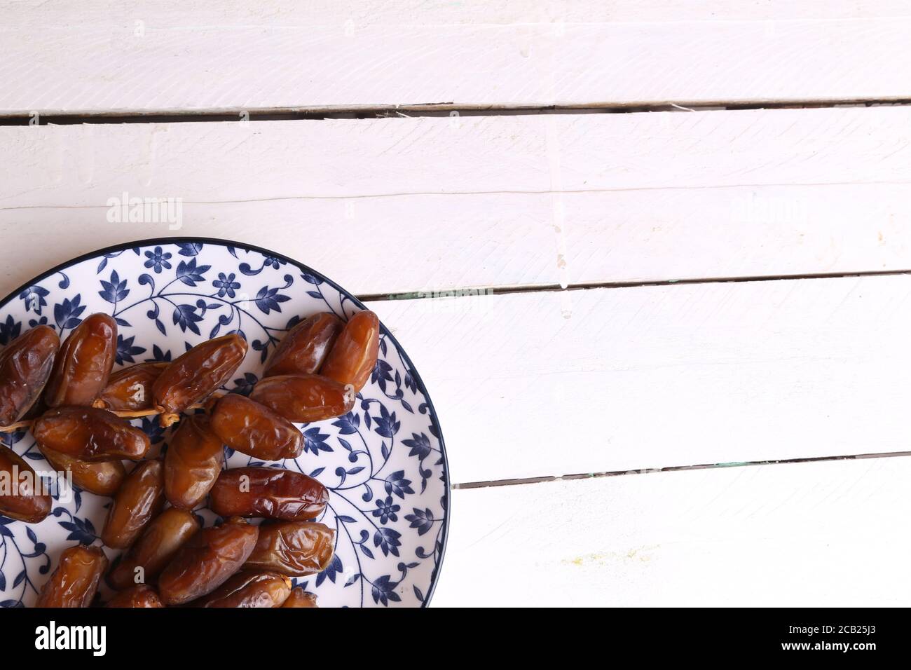 Top view of a plate of dry fruits dates isolated on a white wooden ...