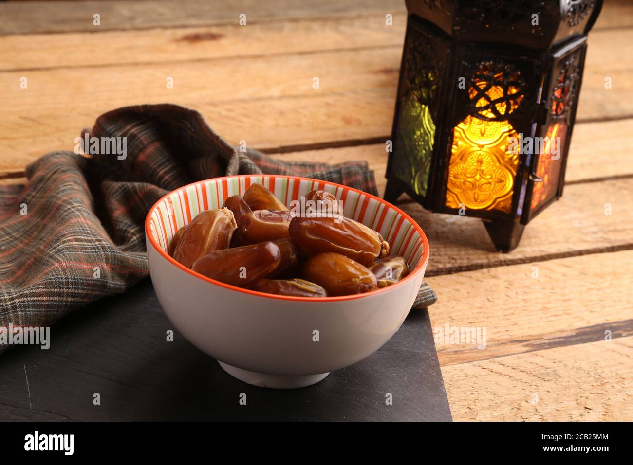Closeup shot of dry dates fruit in a bowl and lantern with a yellow ...