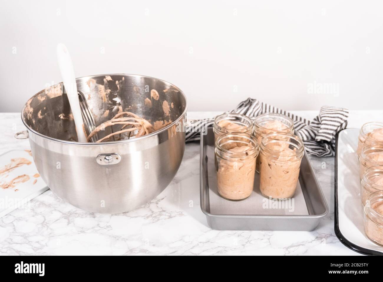 Scooping mixture into the small glass jars to make homemade chocolate ...