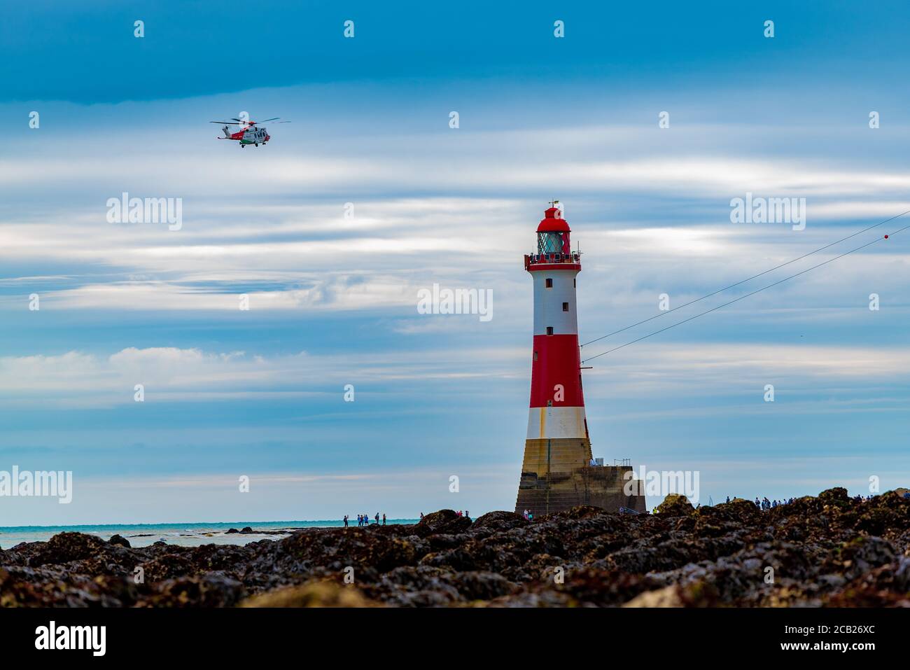 Eastbourne lighthouse at low tide with coast guard helicopter overhead ...