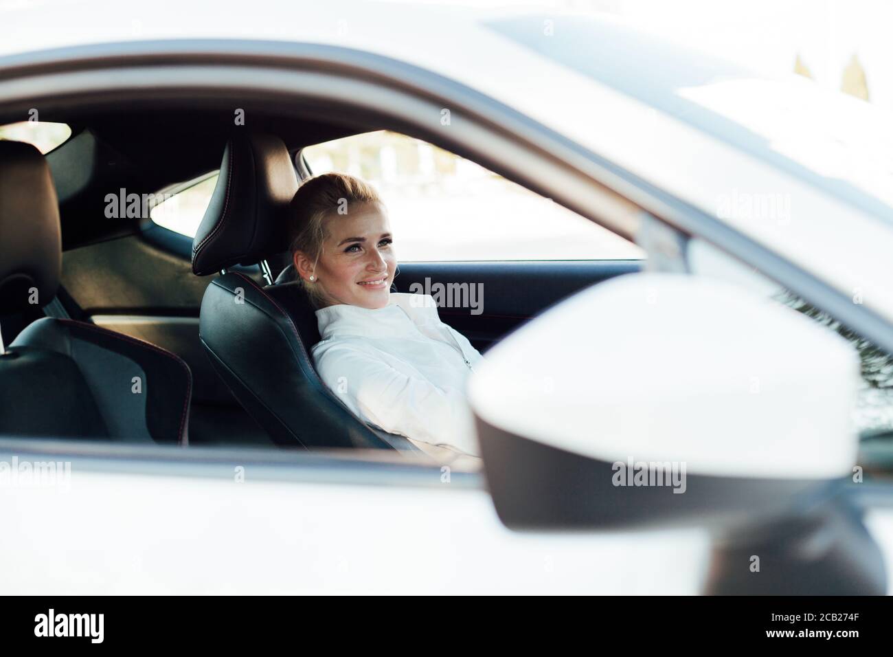 Beautiful female blonde driver behind the wheel of a white car Stock ...