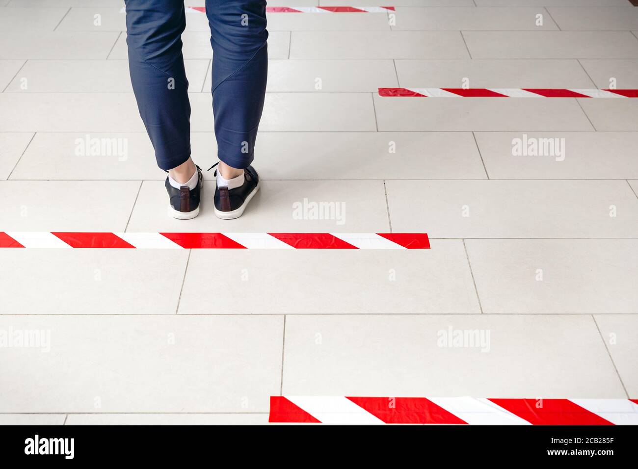People stand in line keeping social distance, standing behind warning ...