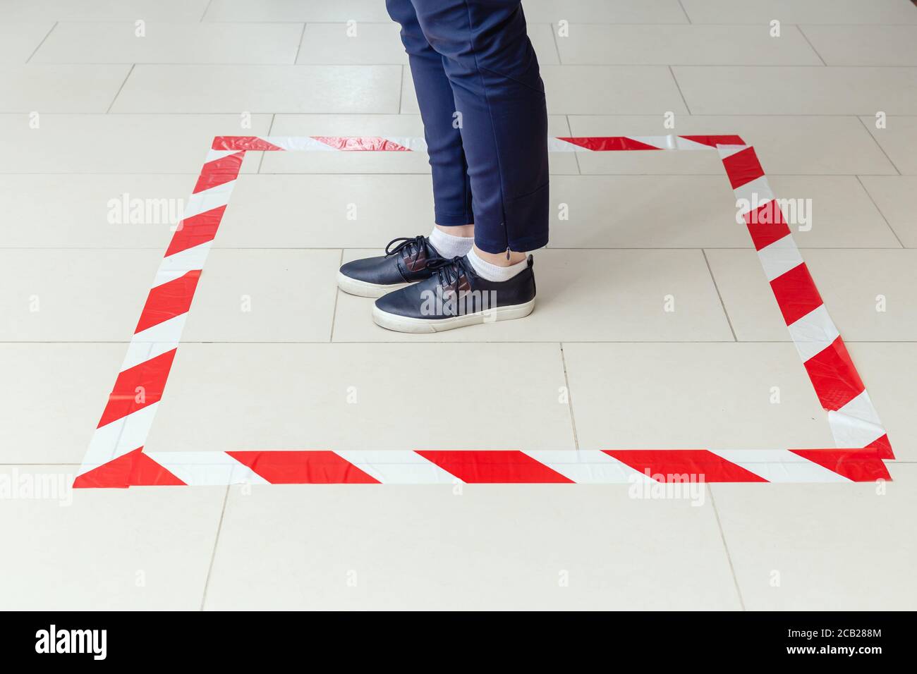 Person stand in line keeping social distance, standing behind warning ...