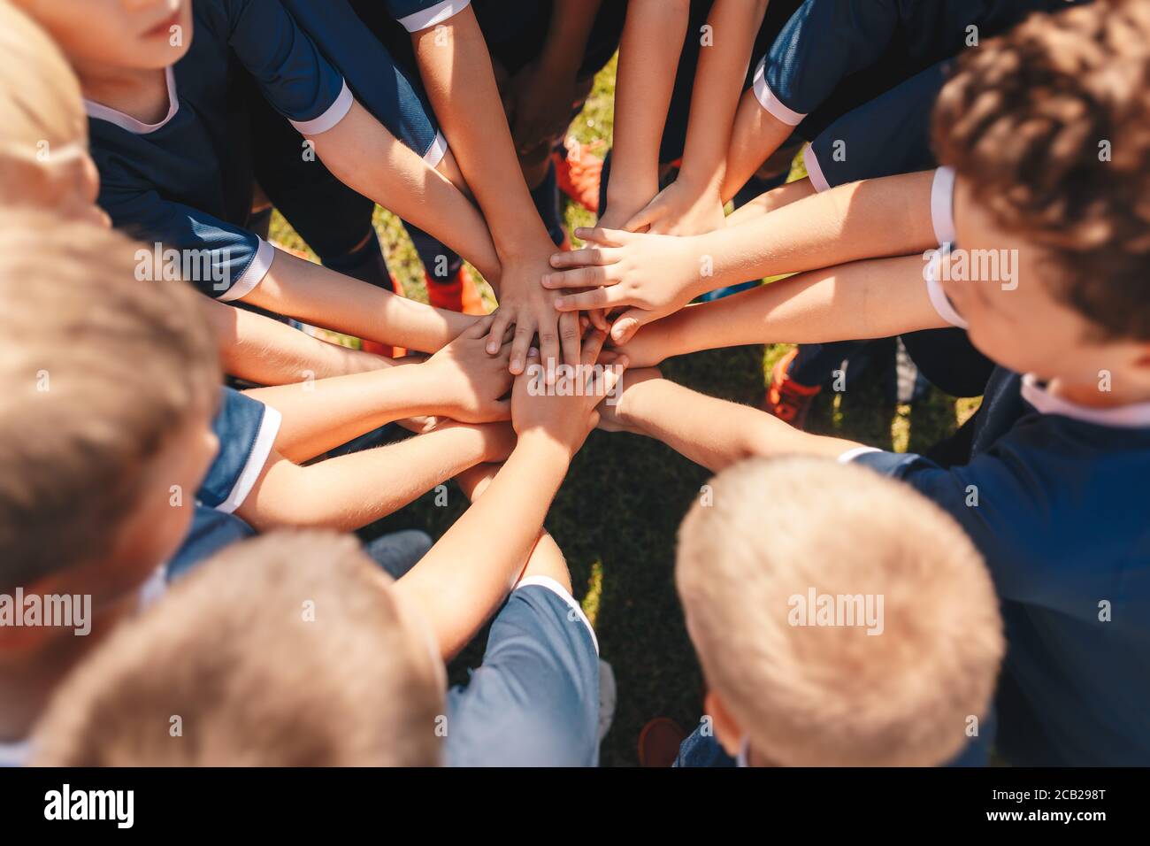 Happy kids sports team stacking hands at the field. Children team ...