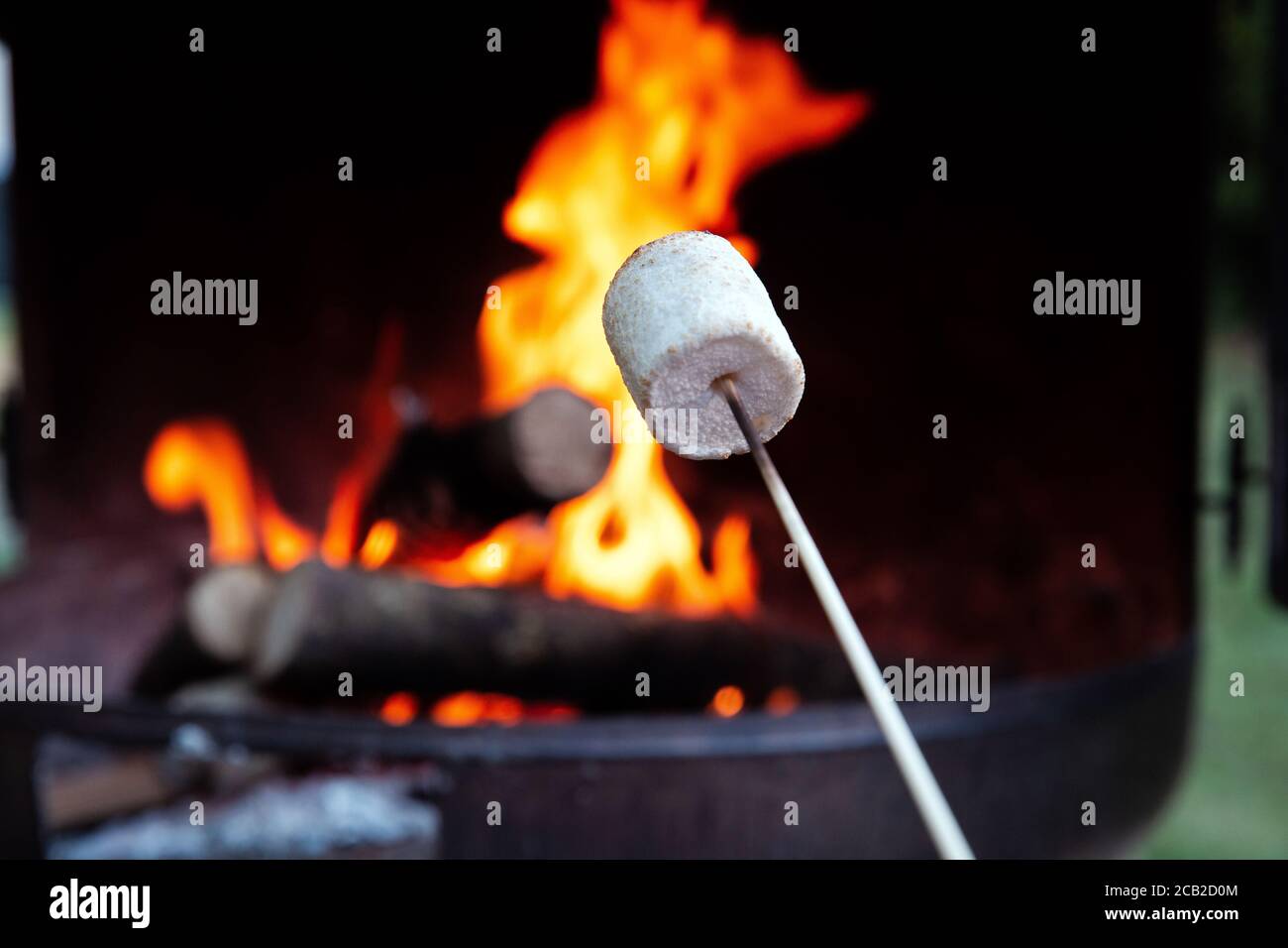 Person roasting over fire flames a marshmallows over campfire at night ...