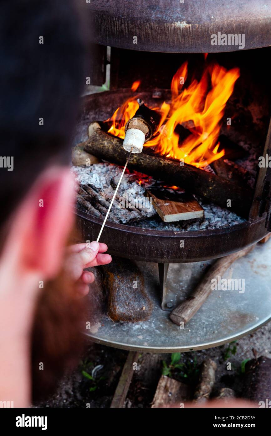Person roasting over fire flames a marshmallows over campfire at night ...