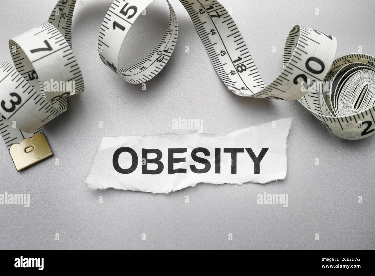 Obesity written on a piece of paper with a tape measure lying next to ...