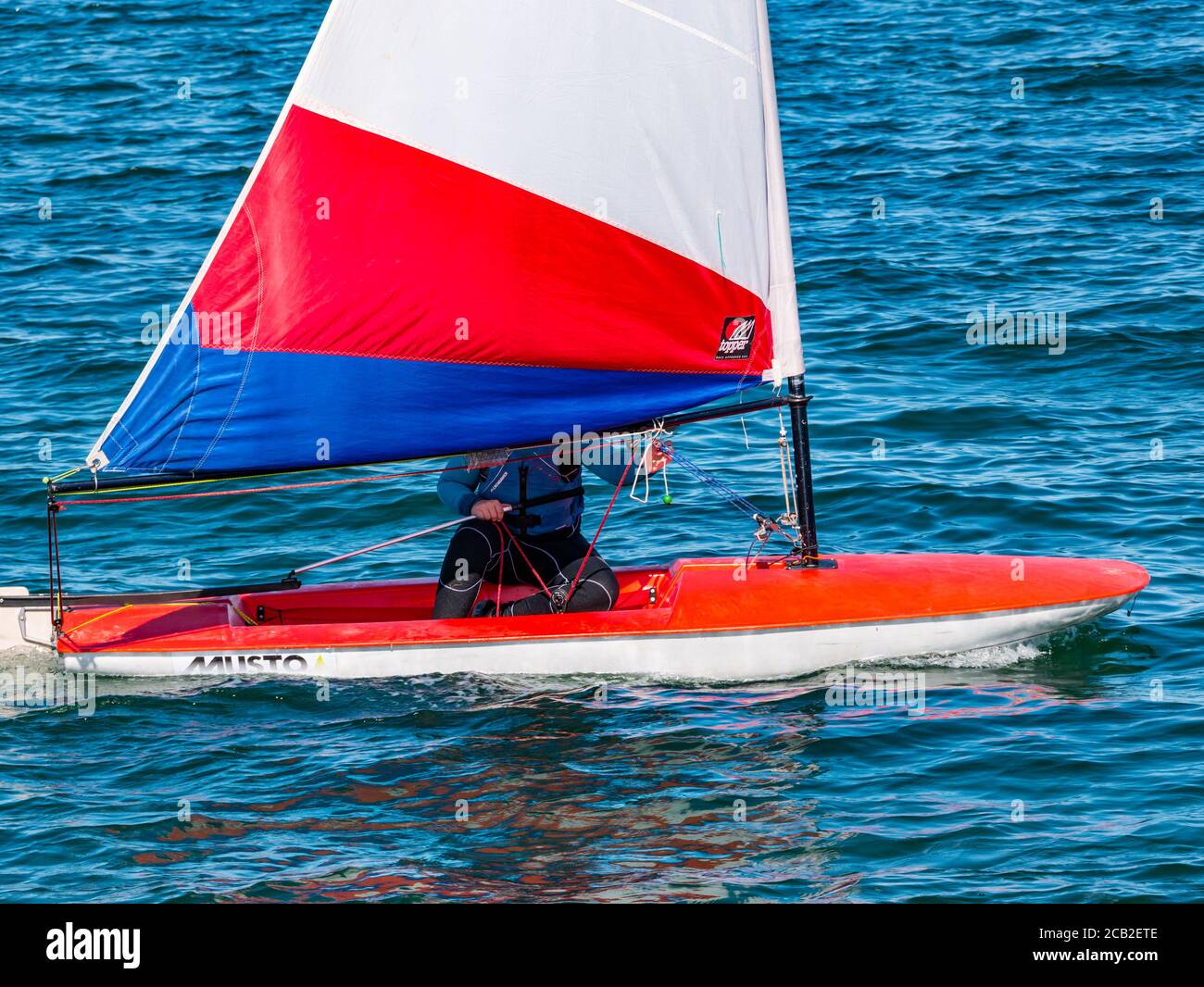 Boy sailing topper sailing dinghy in Firth of Forth on sunny Summer day ...