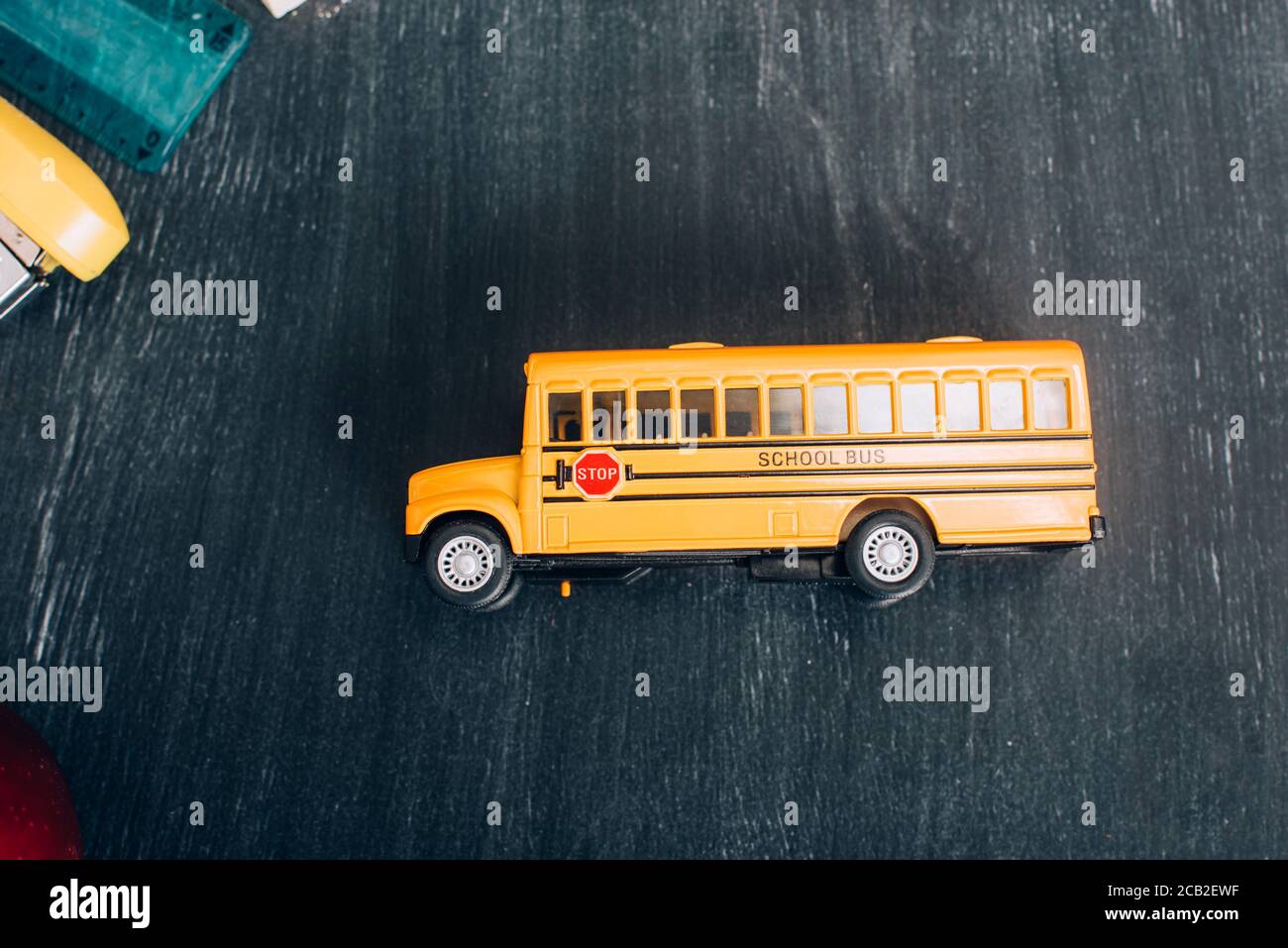 top view of yellow school bus model with stop sign on black chalkboard ...