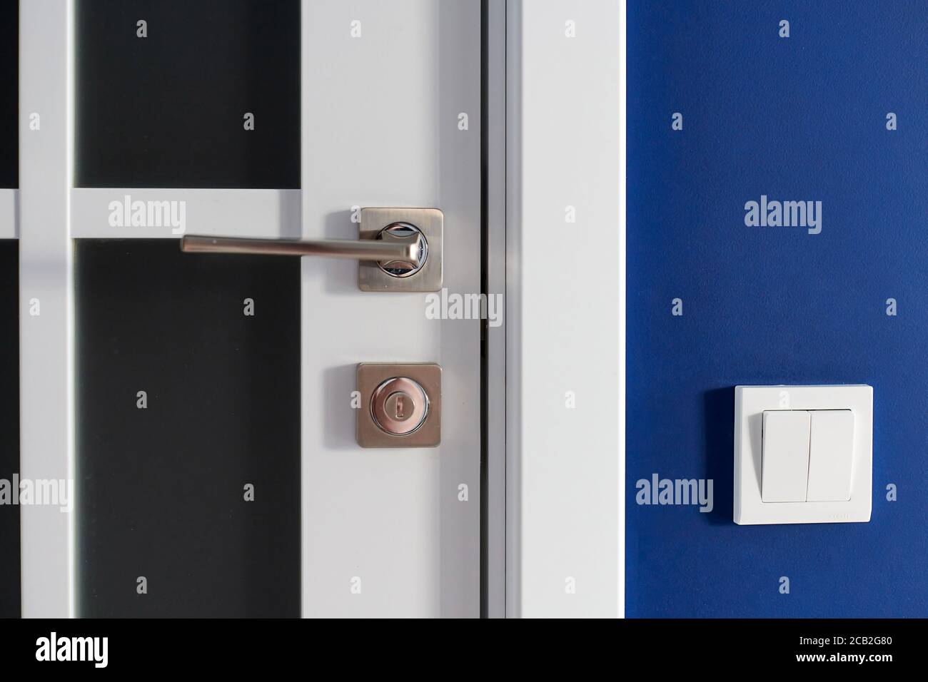 White interior door with handle. Blue wall in modern apartment, light ...