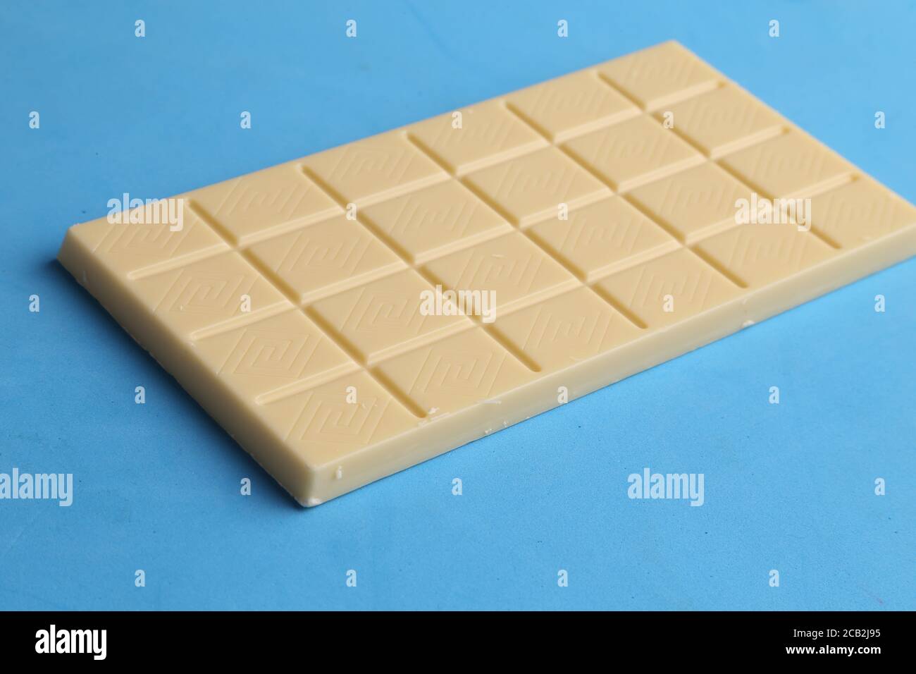 High angle shot of a bar of white chocolate isolated on a blue surface ...