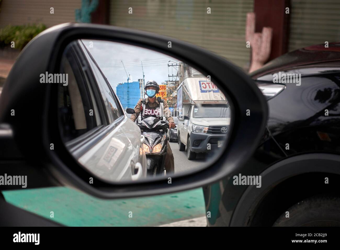 Wing mirror reflection of a car showing a following policeman on a ...