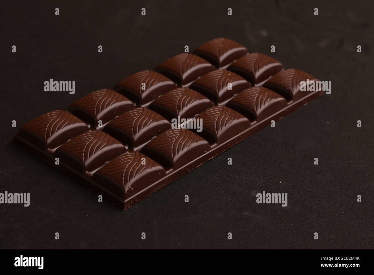 Dark chocolate bar isolated on black background Stock Photo - Alamy