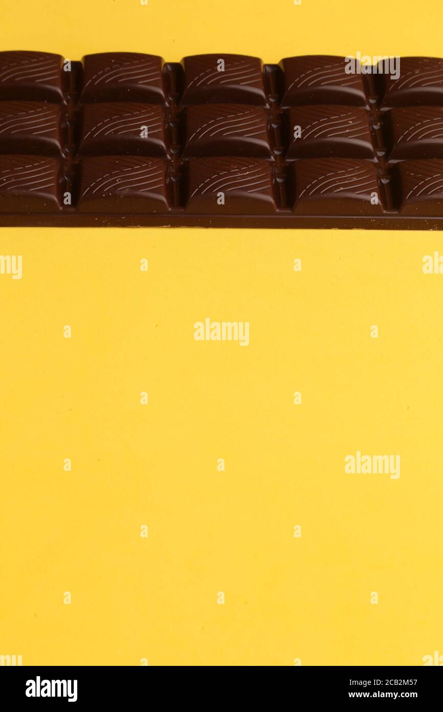 Vertical shot of a dark chocolate bar on yellow background Stock Photo ...