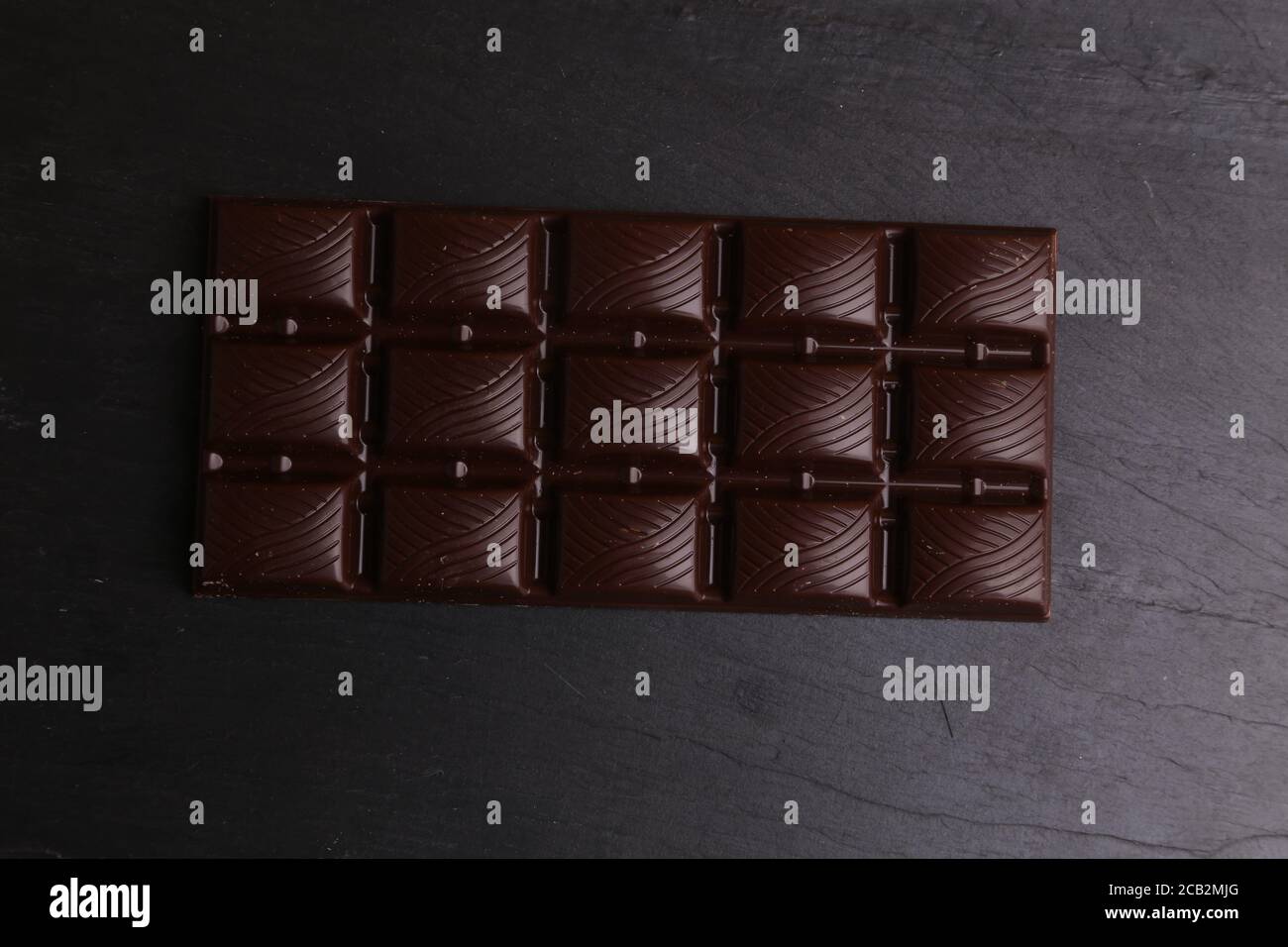 Closeup of a dark chocolate bar on a black background Stock Photo - Alamy