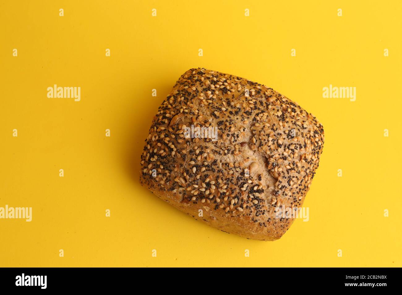 Delicious brown bread covered in sesame seeds on the yellow surface ...
