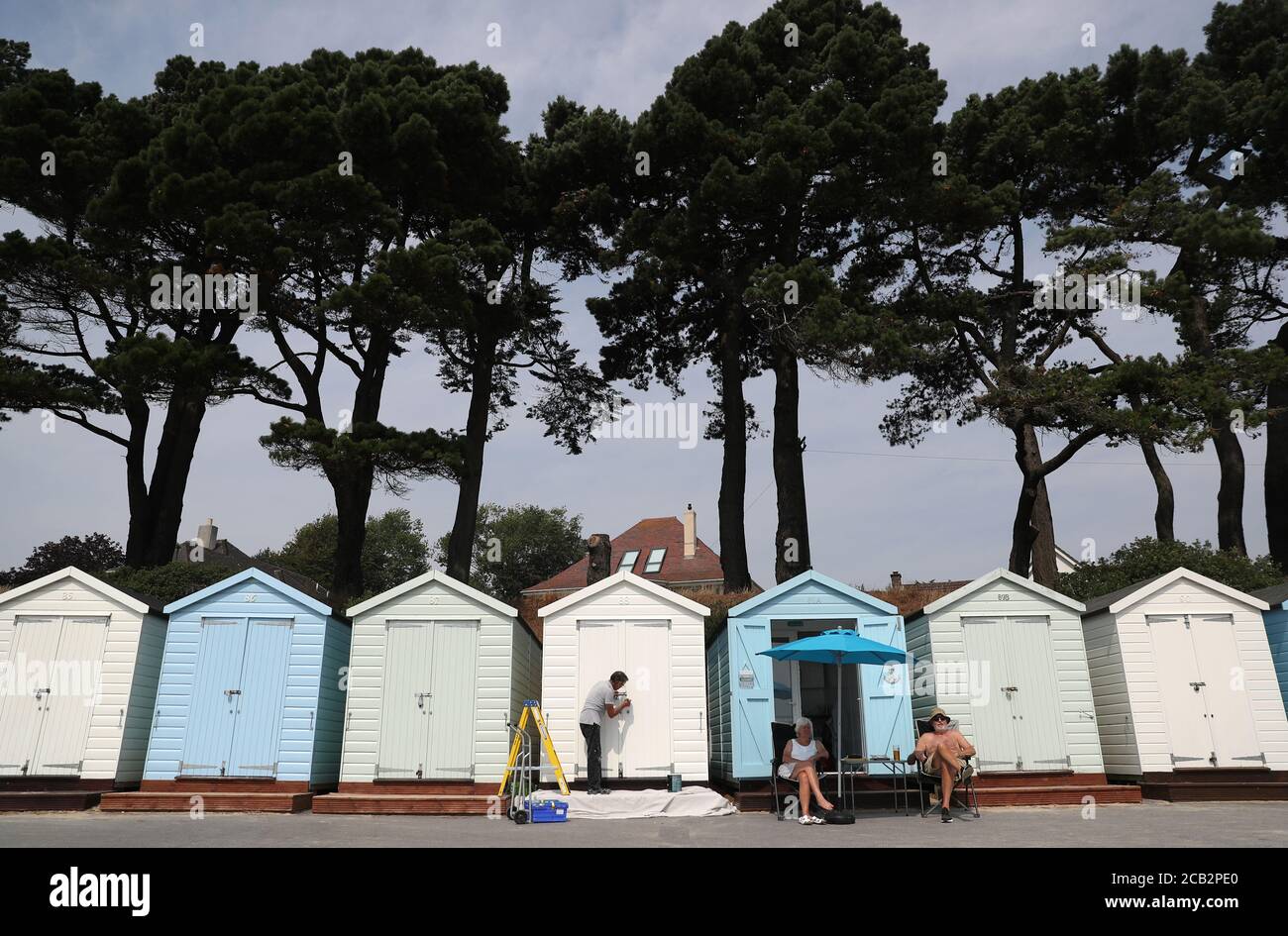 A person paints their beach hut on Avon beach in Mudeford, Dorset Stock ...