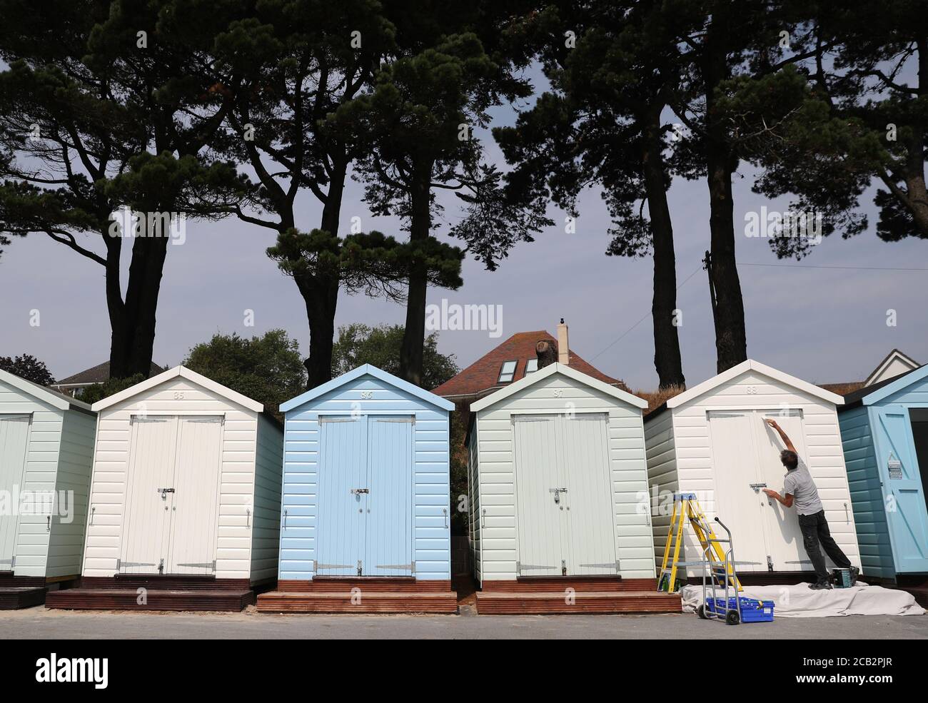 A person paints their beach hut on Avon beach in Mudeford, Dorset Stock ...