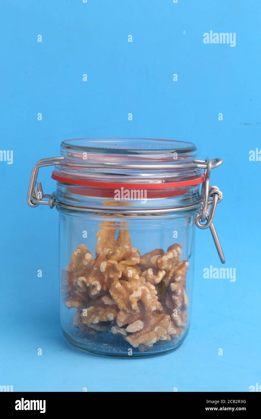 Vertical closeup shot of walnuts in a jar on a blue background Stock ...