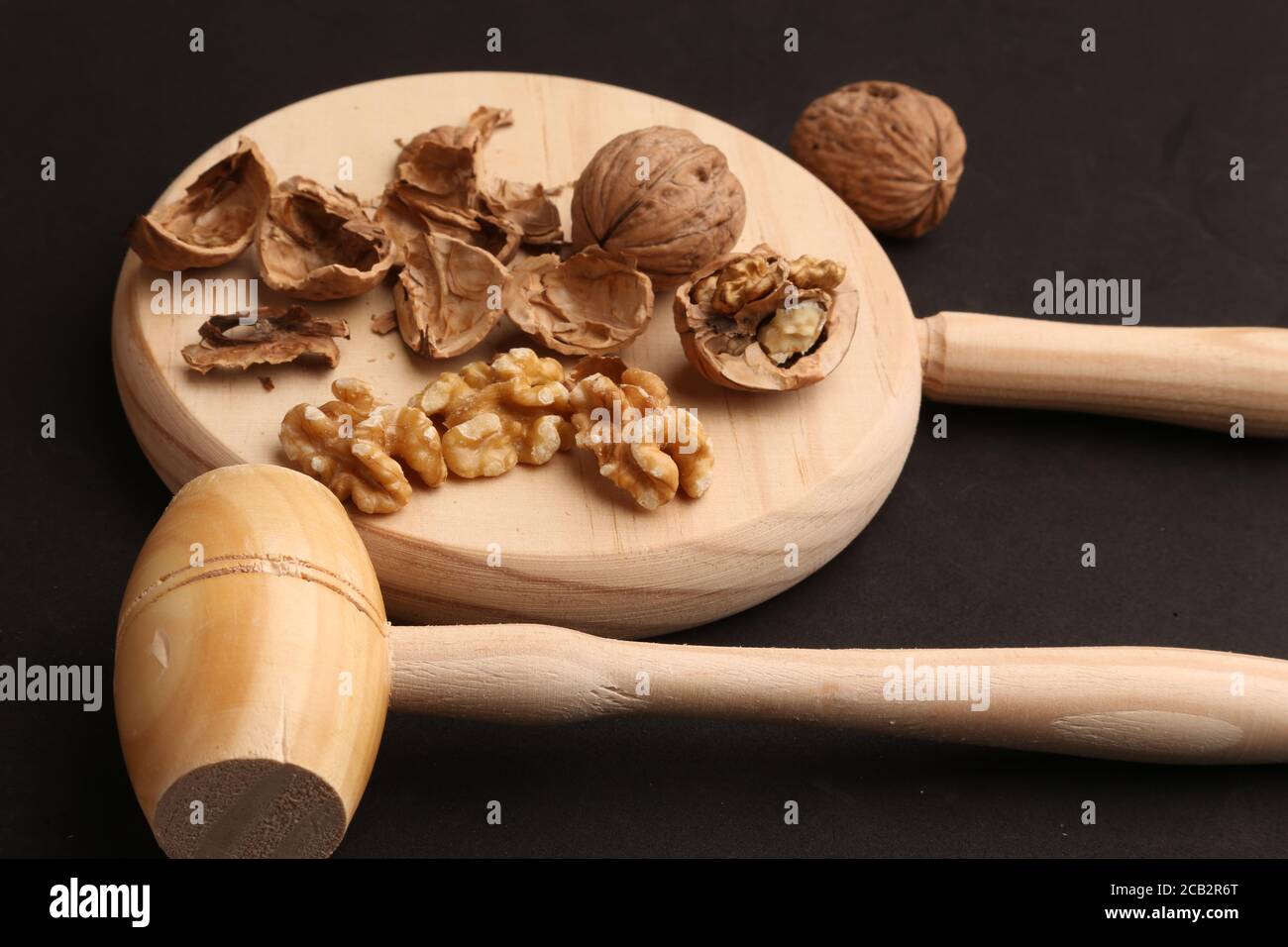 Closeup shot of a wooden mallet and a delicious cracked walnut nuts ...
