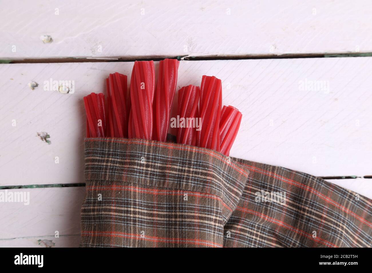 High angle shot of stick candies wrapped in a cloth on a white wooden ...