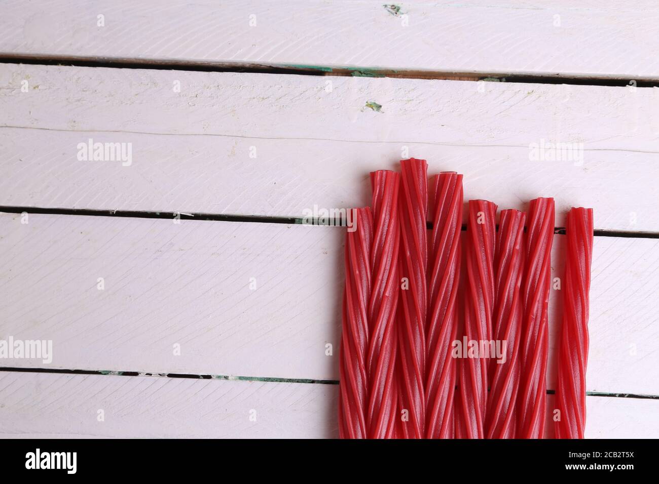 Closeup shot of red licorice sticks on a white wooden surface Stock ...