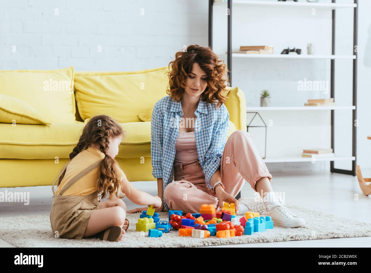 beautiful nanny and child sitting on floor in living room and playing ...